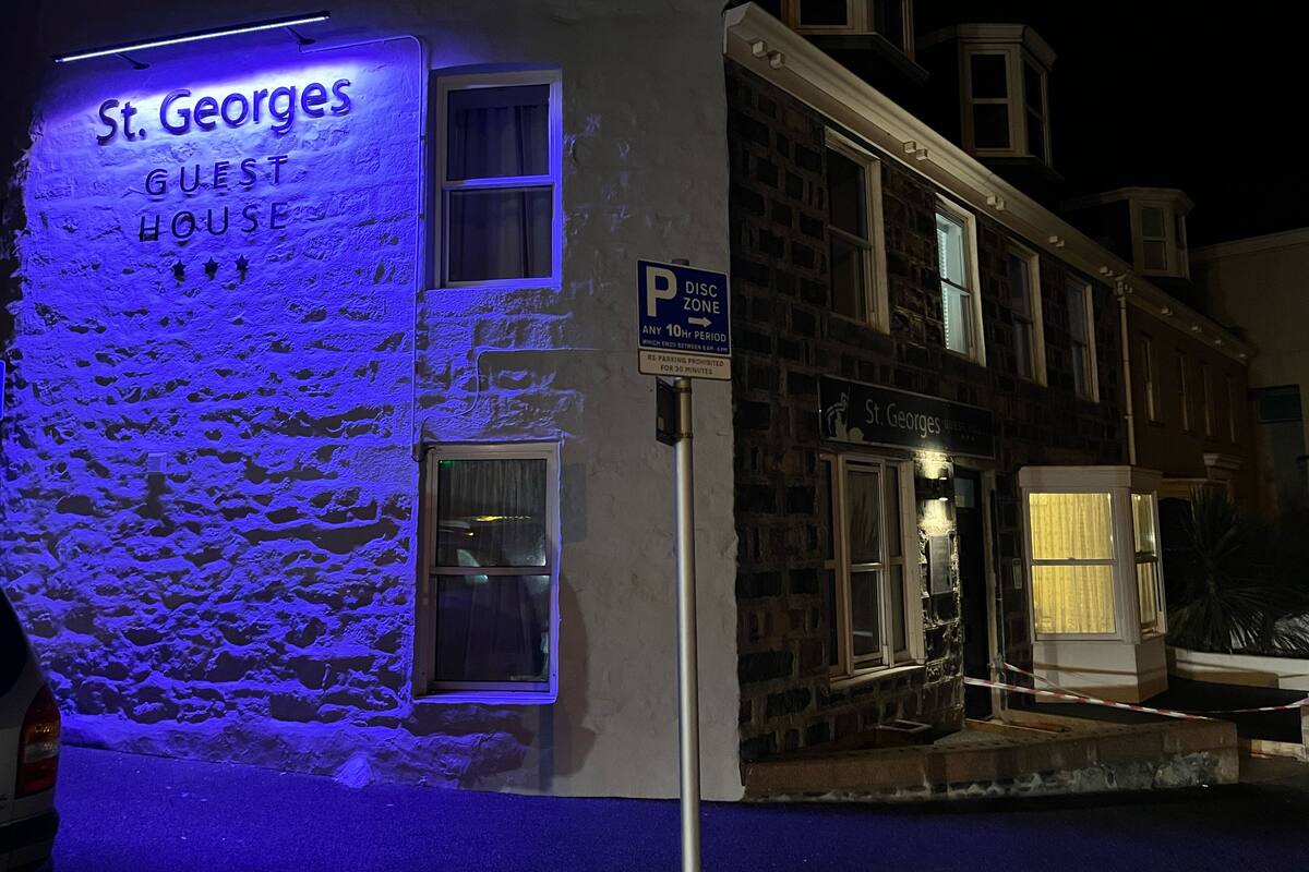 Um edifício com uma placa com a inscrição "St. Georges Guest House" e uma placa de estacionamento indicando uma zona de estacionamento de 10 horas.