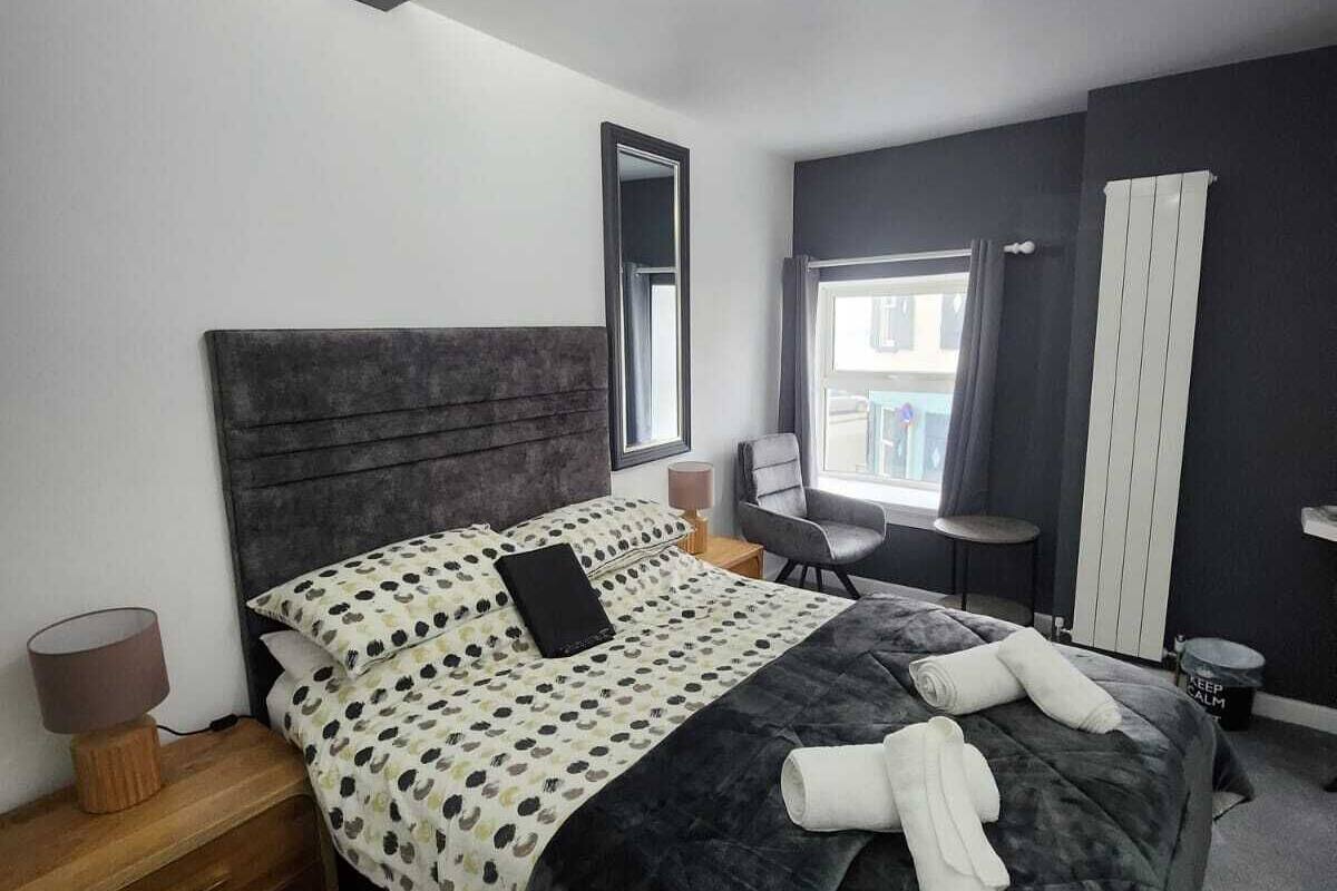 Um quarto moderno com uma cama grande, mesas de cabeceira, uma cadeira e uma janela.