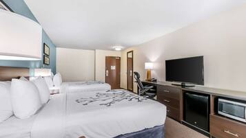 Quarto de hotel com duas camas, televisão, escrivaninha e uma cadeira.