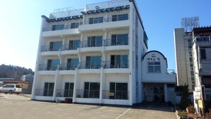 Um edifício de vários andares com fachada branca, várias varandas e céu claro.