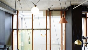 Um interior moderno com escada, guarda-corpos de vidro e iluminação pendente.