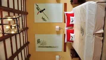 Quarto de hotel com cama, mesa de cabeceira e duas obras de arte penduradas na parede.