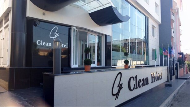 Um hotel chamado 'Clean Hotel', com fachada moderna, janelas amplas e entrada limpa.