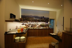 Uma área de buffet com vista para a cidade, balcão de madeira e diversos tipos de comida.
