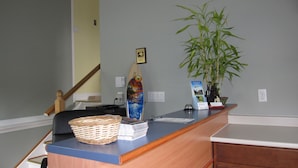 Uma mesa de recepção com uma cesta de vime, uma prancha de surf e um vaso com planta.
