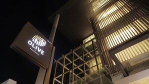 Um edifício moderno com fachada envidraçada e uma placa com o texto 'Olive Residence'.