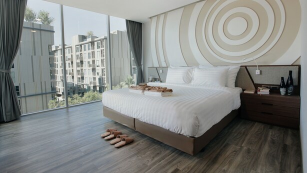 Quarto de hotel moderno com uma cama grande, piso de madeira, vista da cidade e design circular nas paredes.