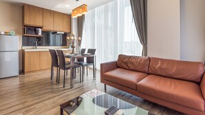 Uma sala de estar moderna com sofá de couro, mesa de jantar com cadeiras, cozinha com armários de madeira e uma grande janela com cortinas.
