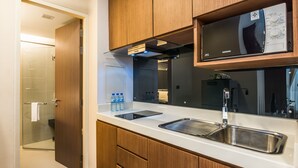 Cozinha moderna com armários de madeira, pia de aço inoxidável e micro-ondas Samsung.