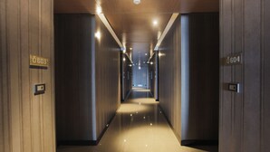 Um corredor moderno com piso polido e painéis de madeira, com placas iluminadas indicando os quartos 603 e 604.