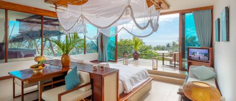 Um quarto amplo com cama, área de refeições e espaço para sentar com vista para o mar.