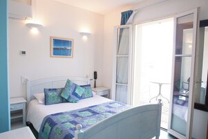 Quarto com cama, mesas de cabeceira, um aparador, janela com cortinas e vista para o exterior.