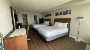 Quarto de hotel com duas camas, uma mesa, um guarda-roupa e um espelho.