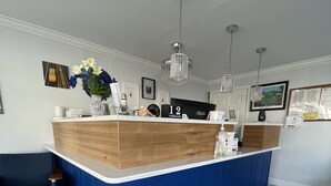 Uma área de recepção com balcão de madeira, piso de mármore e uma parede azul decorativa.