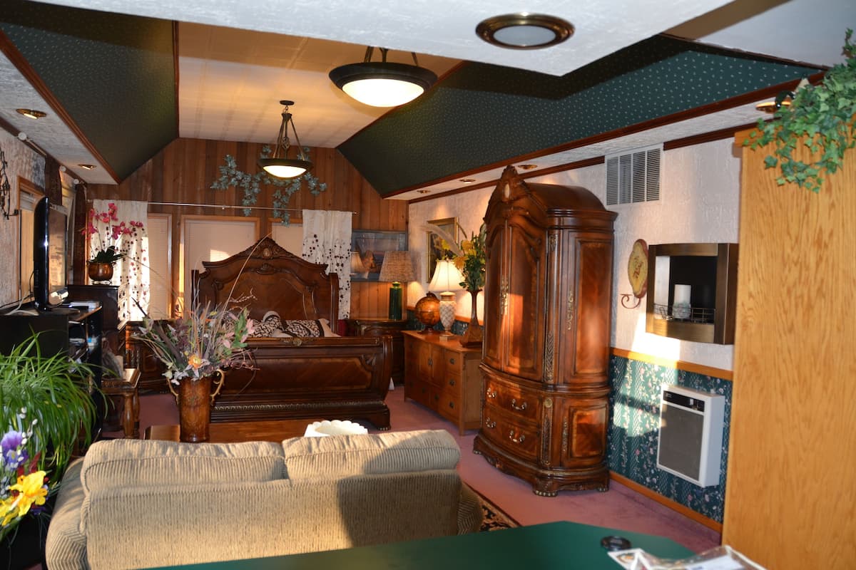 Quarto tradicional com uma cama de madeira grande, um armário de madeira, uma mesa pequena e um sofá.