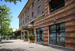 Um hotel com fachada de tijolos, área de estar externa e uma placa com a inscrição "HOTEL ANOETA".