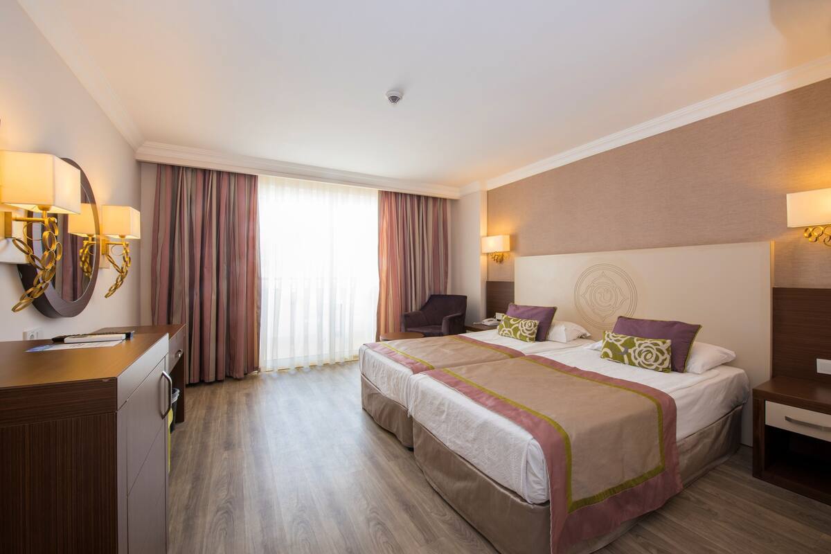 Quarto de hotel com uma cama grande, uma mesa, uma cadeira e uma luminária de mesa.
