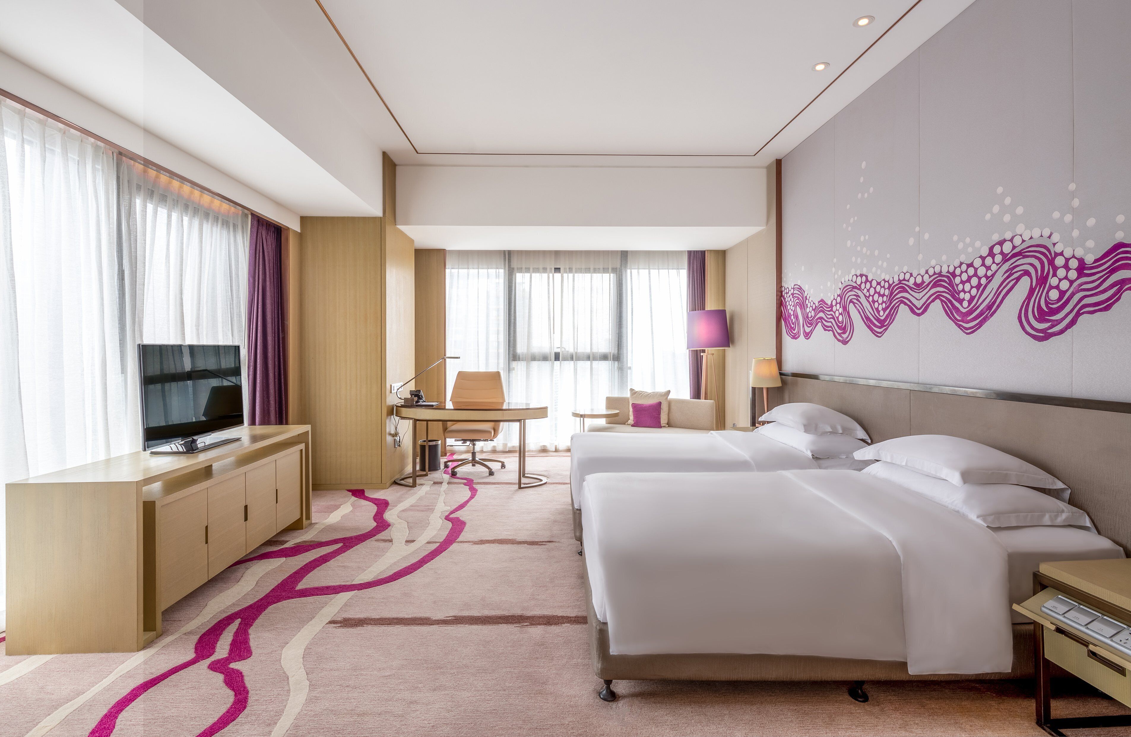 Quarto de hotel com cama, escrivaninha, televisão e vista para a cidade.