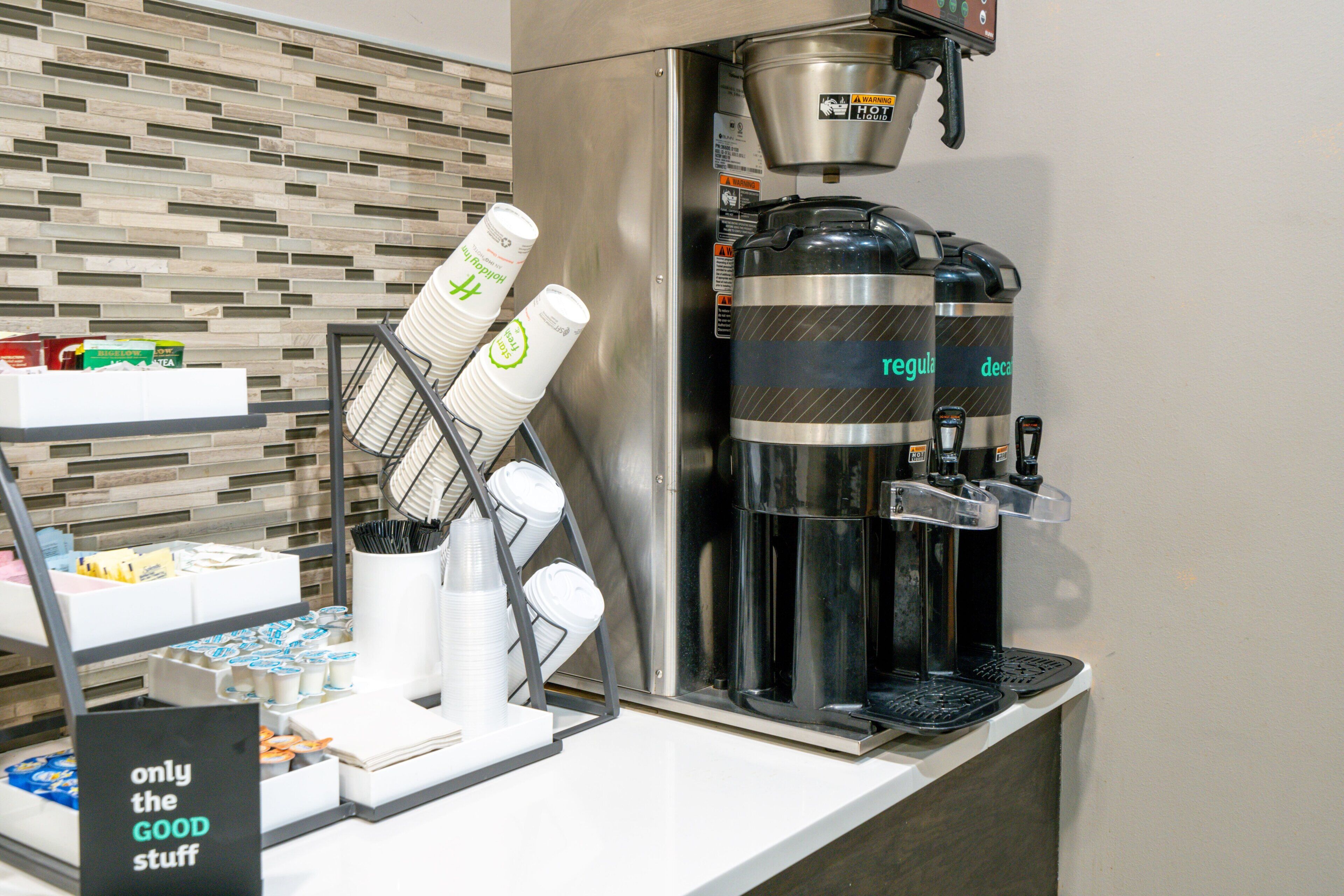 Uma estação de café com máquina de café, chávenas e um letreiro com a inscrição 'só o melhor'.