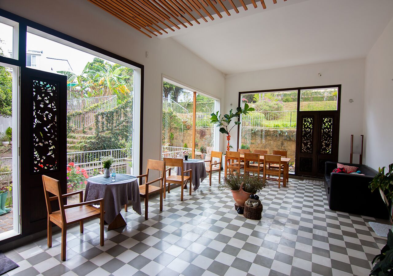 Um quarto espaçoso com piso xadrez, janelas amplas e varanda com vista para o verde.