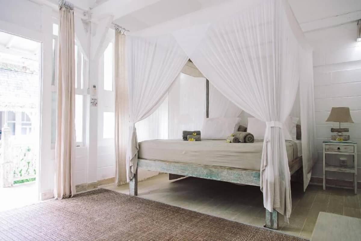Uma cama com dossel, uma mesa de cabeceira e vista para o exterior.