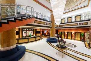 Um hall amplo com uma escadaria imponente, uma mesa de recepção e uma área de estar.