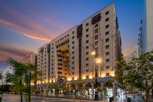 Um hotel com vários andares, entrada imponente, janelas amplas e fachada bem iluminada.
