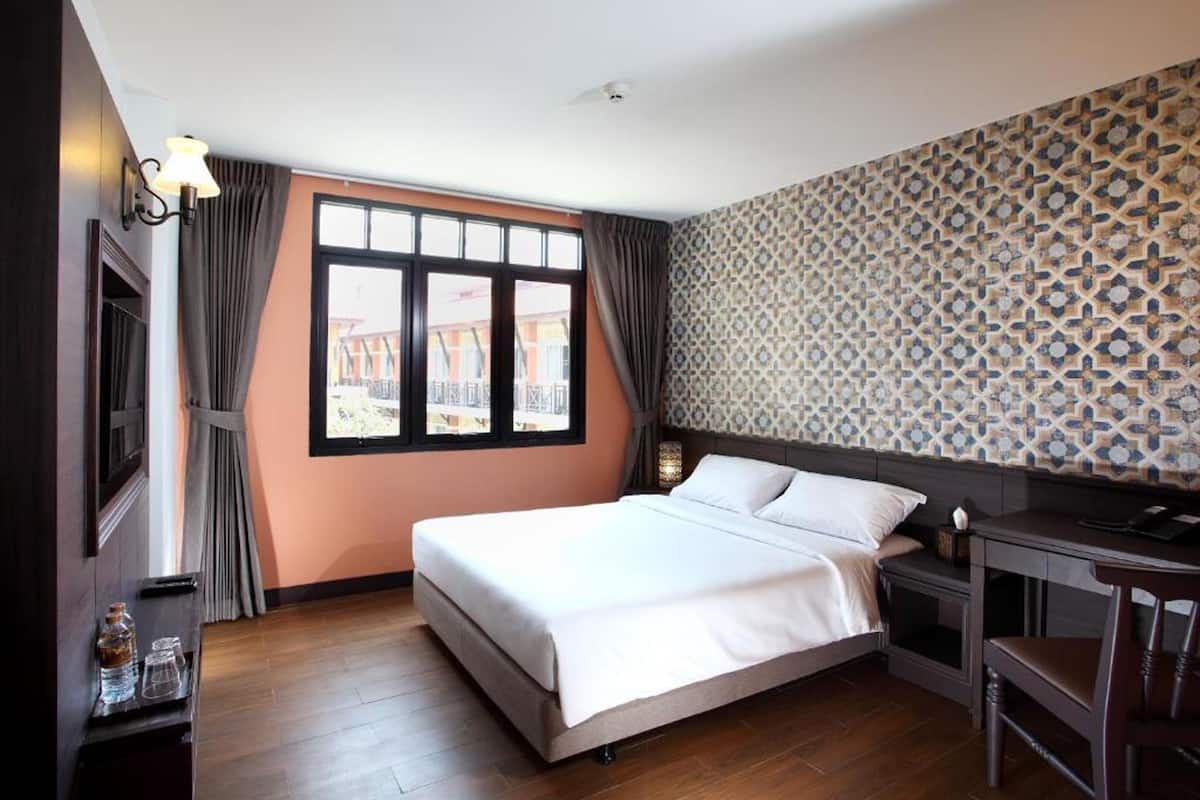 Quarto de hotel com uma cama grande, uma mesa e vista para edifícios pela janela.