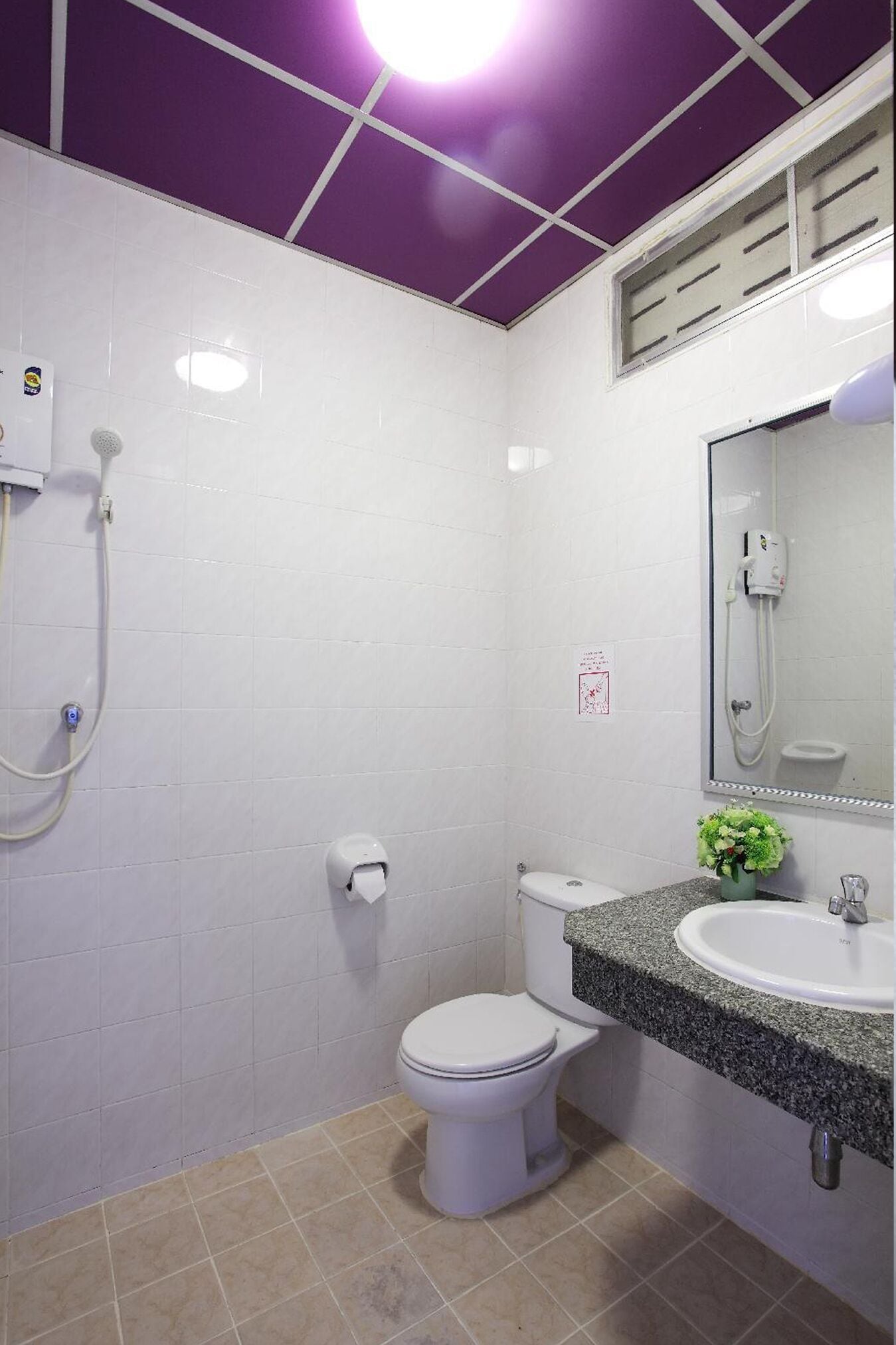 Casa de banho com azulejos brancos, teto roxo, sanita, lavatório e chuveiro.
