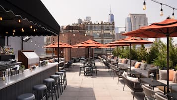 Um pátio externo com assentos, área de bar e vista para a cidade.