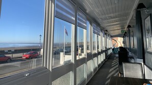 Um corredor com amplas janelas, vista para a praia, e uma bandeira do lado de fora.