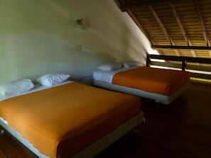 Quarto com duas camas, cada uma com almofada branca e manta laranja.