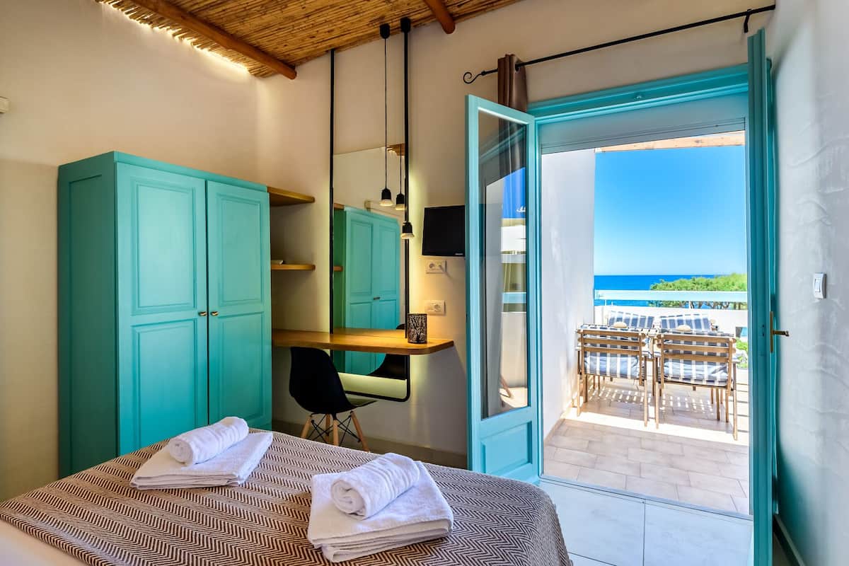 Quarto com cama, escrivaninha e banheiro com chuveiro.