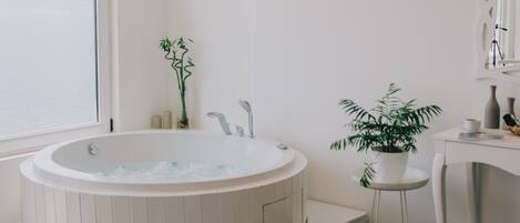 Um banheiro moderno com uma banheira separada, um lavatório com espelho e um vaso de planta.