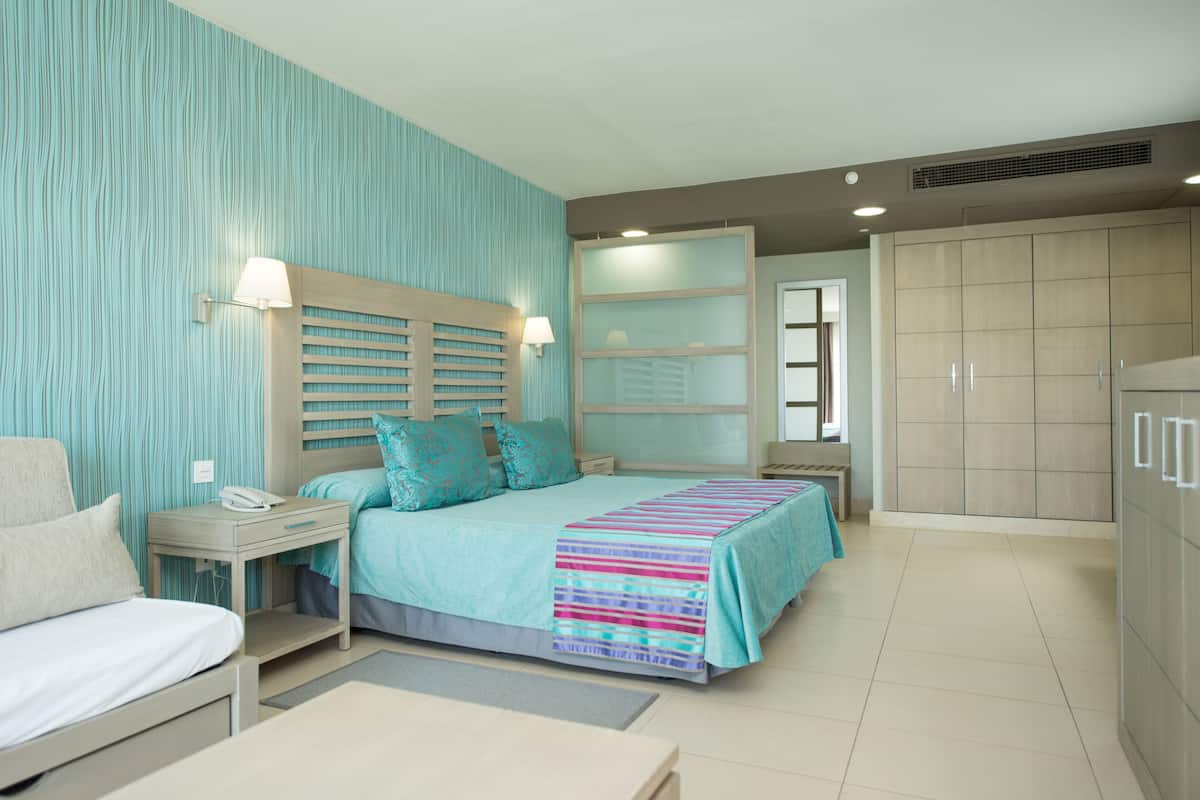 Quarto com cama, mesas de cabeceira, criado-mudo, guarda-roupa e janela.