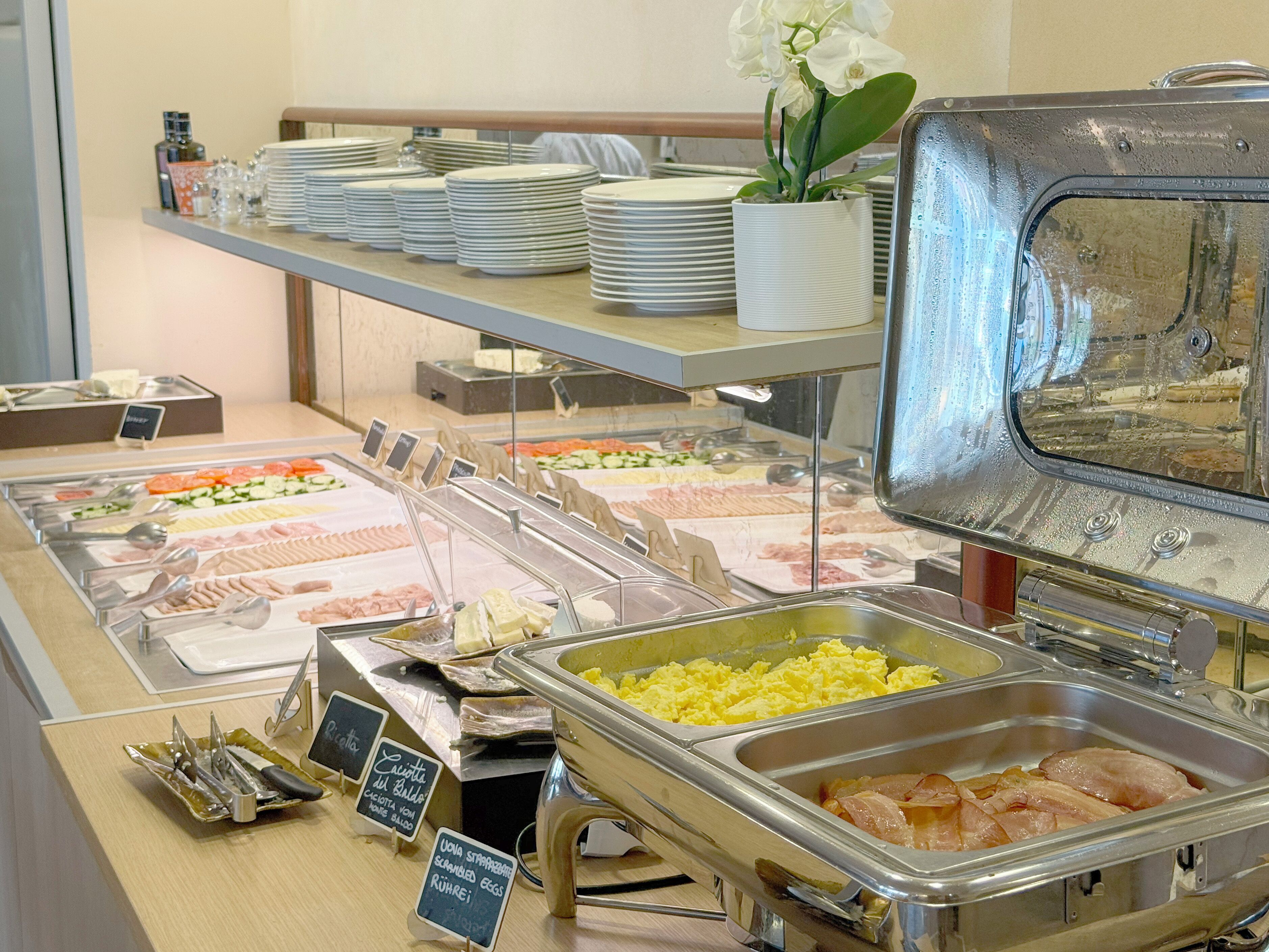 Buffet com diversas opções de comida, incluindo carnes, ovos e saladas.