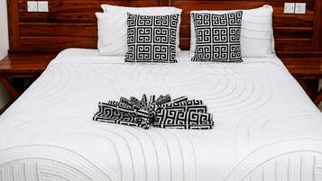 Cama bem arrumada com colcha estampada e almofadas, cabeceira de madeira e arte decorativa na parede.