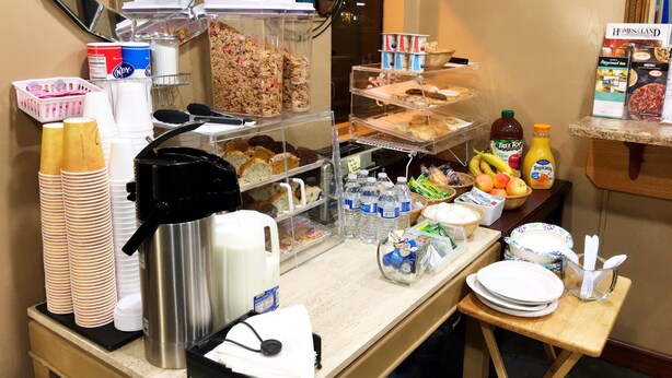 Um balcão de café da manhã com diversas opções de alimentos, incluindo cereais, pães e bebidas.