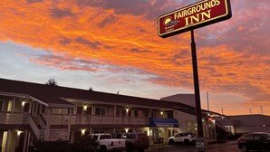 Um motel com um letreiro que diz "Fairground Inn" sob um céu ao pôr do sol.