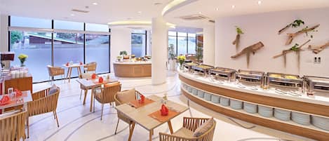 Um saguão de hotel moderno com área de buffet, mobiliário de madeira e grandes janelas com vista para o exterior.