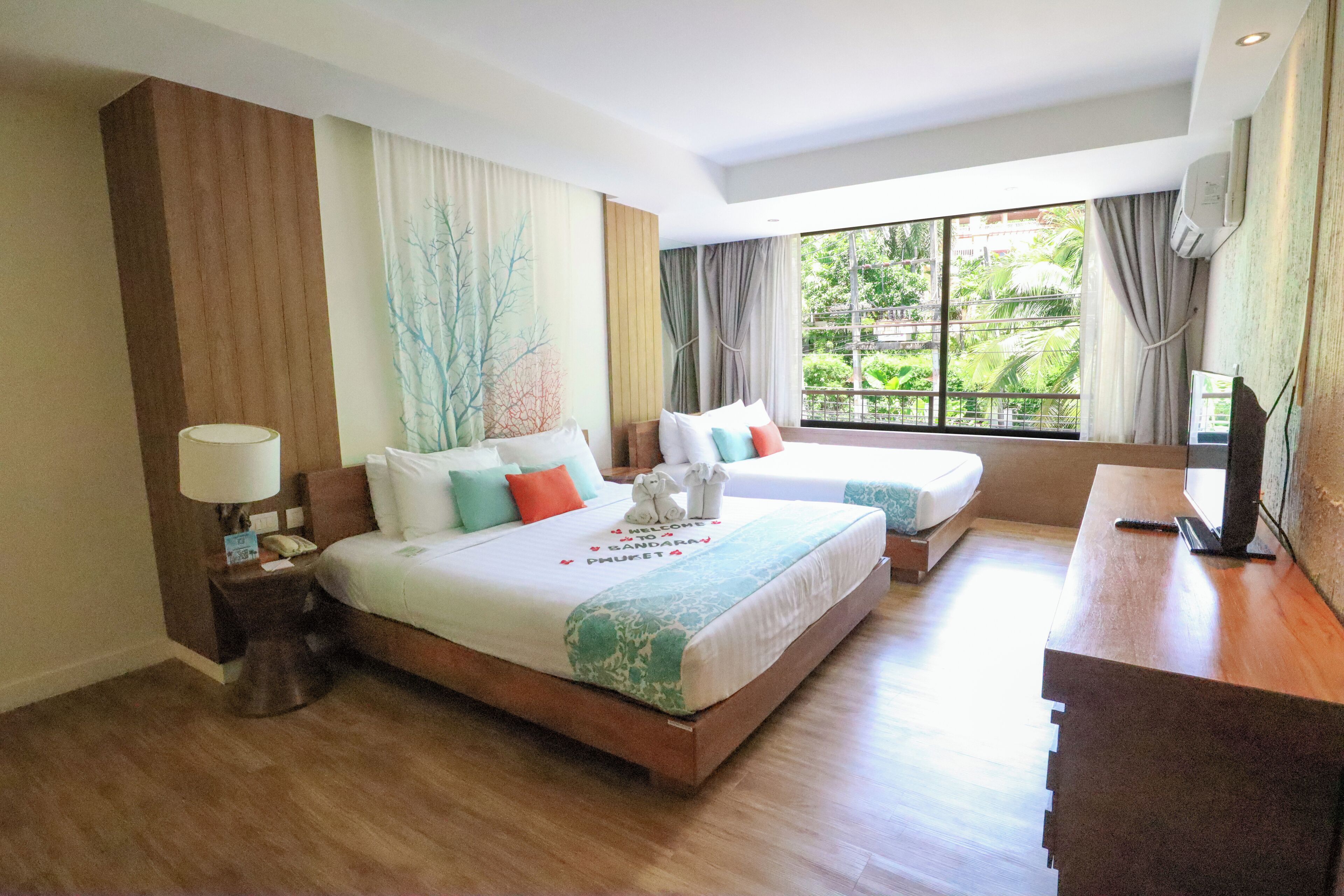 Quarto de hotel com uma cama grande, uma escrivaninha e uma televisão.