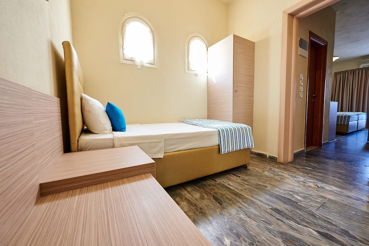 Quarto de hotel moderno com cama, um banco de madeira e um guarda-roupa.