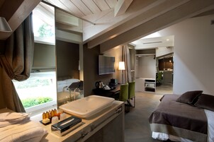 Quarto de hotel com cama, banheiro com pia, escrivaninha e uma cadeira.