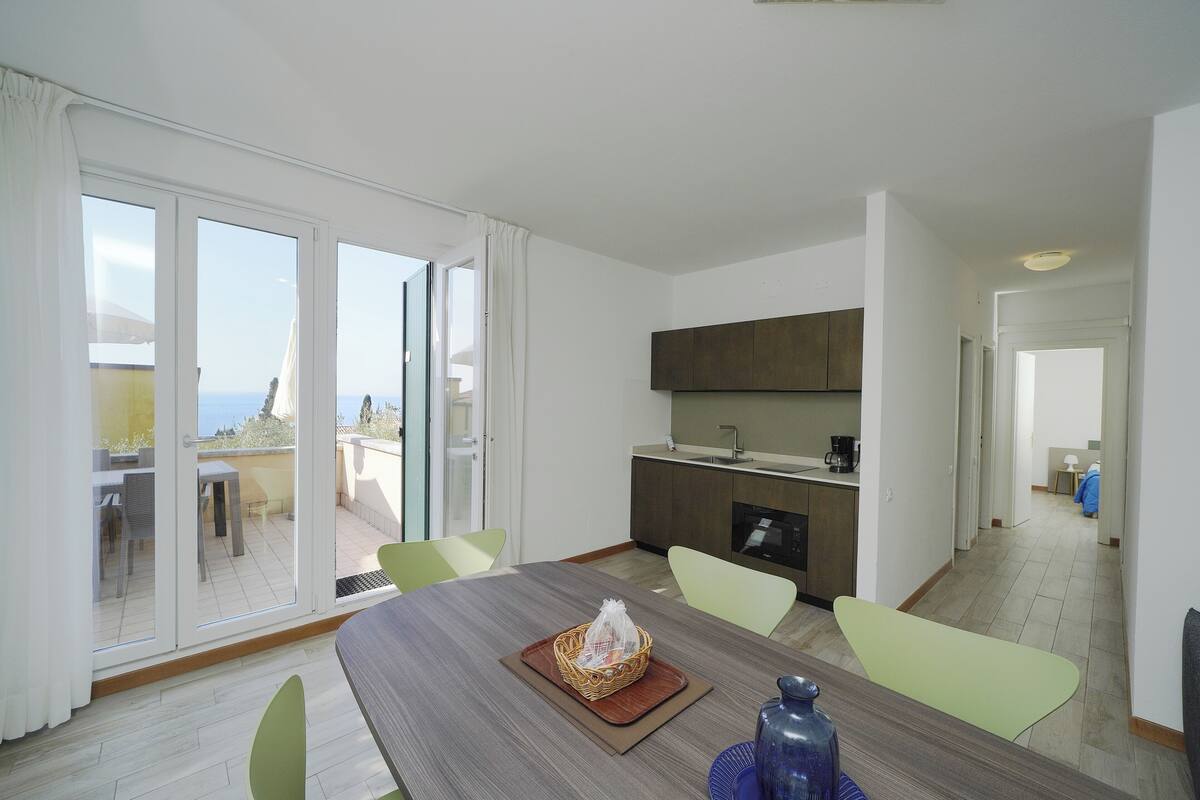 Uma sala de jantar com mesa, cadeiras e vista através de uma porta de vidro.