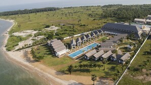 Vista aérea de um resort com praia, piscina e várias acomodações no estilo bangalô.