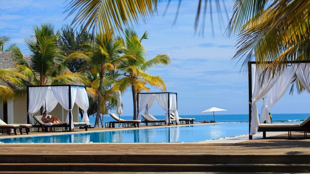 Área da piscina com espreguiçadeiras e vista para o oceano.