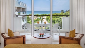 Uma varanda com vista para o oceano, uma mesa de jantar com cadeiras e uma cama com vista.