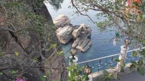 Vista costeira com formações rochosas e um corrimão com vista para o mar.
