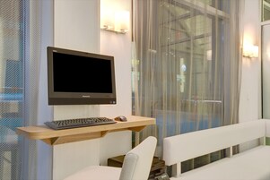 Quarto moderno com escrivaninha, monitor de computador, teclado e rato.