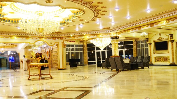 Um hall imponente com lustre, área de estar e placa indicando um lounge.
